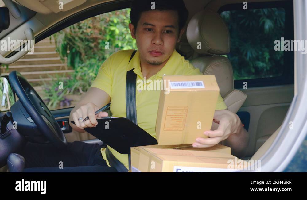Young Asian Delivery man in yellow uniform checking list of package ...