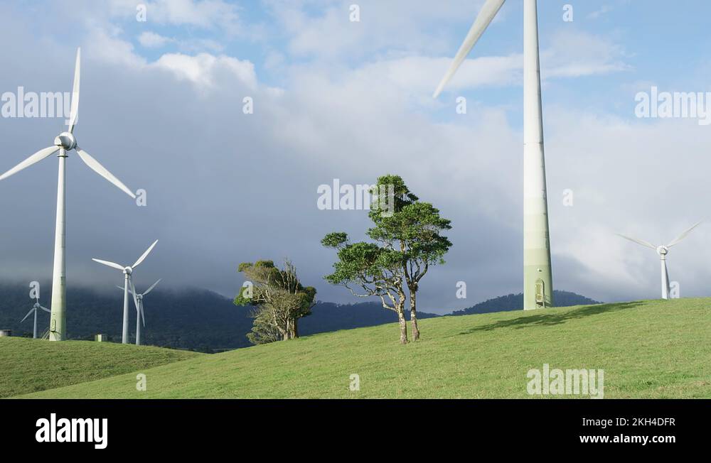 Wind turbine farm at the top of a green hill, high winds with fog ...