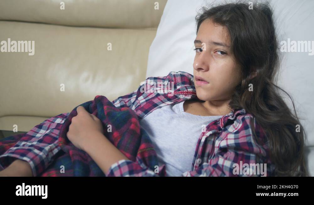 a teenage girl who has caught a cold at home on the couch, she covers ...