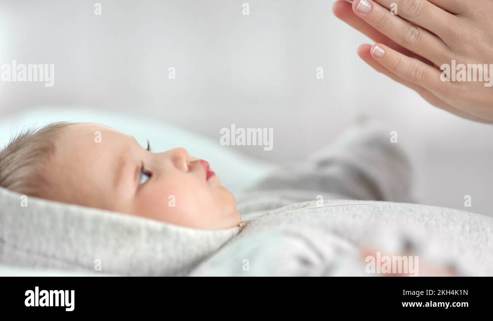 Close-up cute little baby lying on bed clapping hand repeat to mother ...