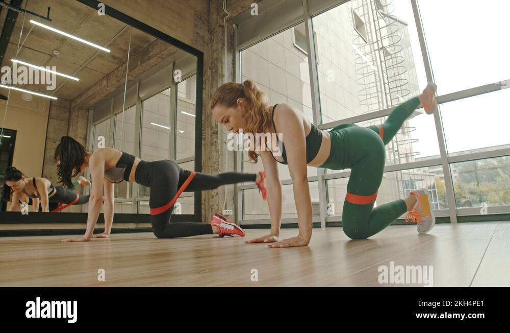 Two healthy women training their legs using a stretching strap between ...