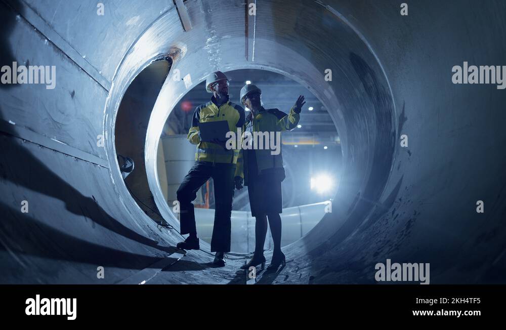 Two Heavy Industry Engineers Walking Inside Pipe, Use Laptop, Have ...