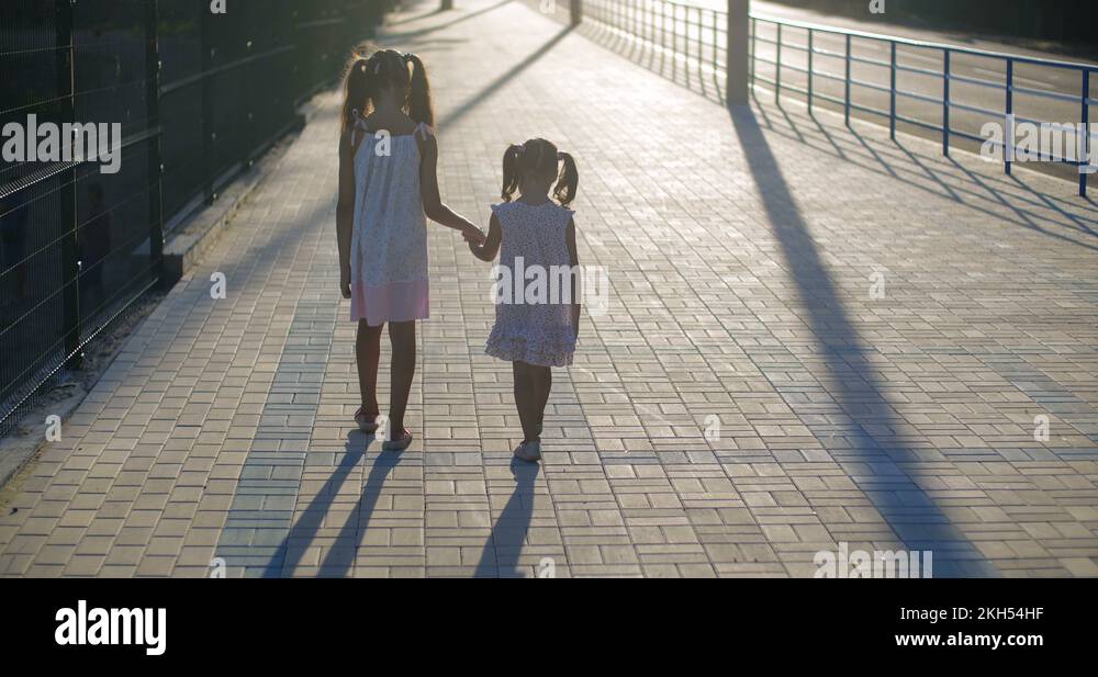 Back view two pretty sisters holding hands along a city street Stock ...