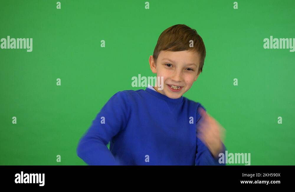 A young cute boy dances and smiles at the camera - green screen studio ...