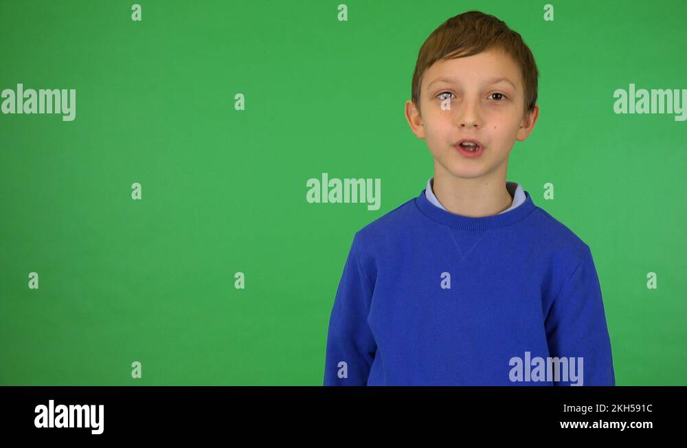 A young cute boy talks to the camera with a smile - green screen studio ...