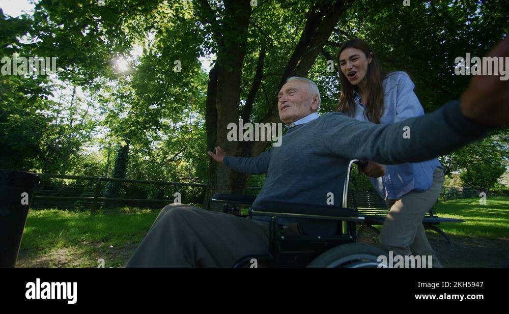 Granddaughter and grandfather in a wheelchair having fun to run in a ...