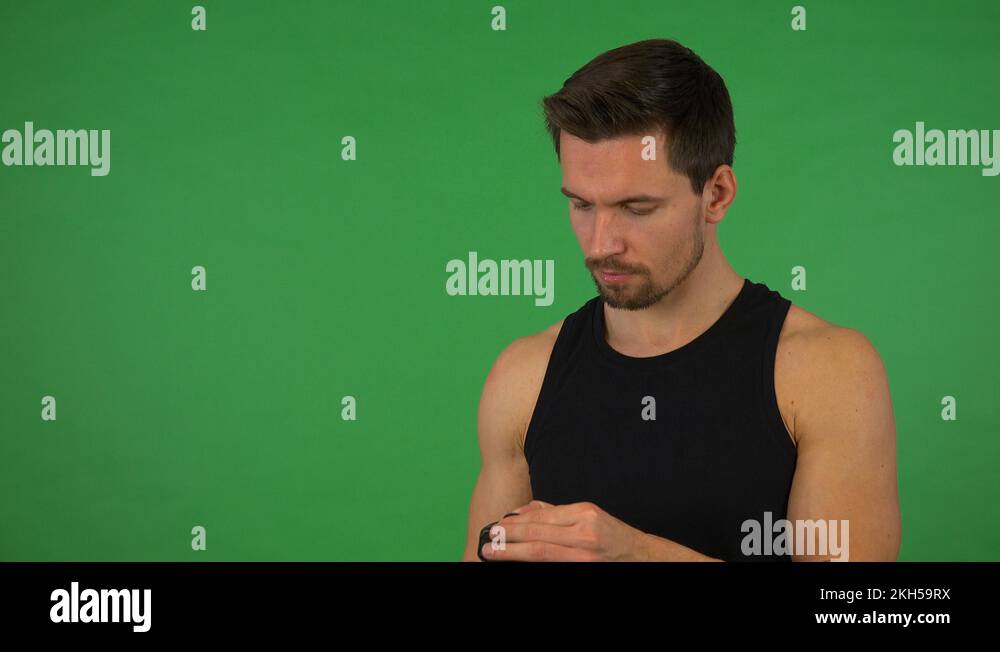 A young handsome athlete drinks from a sport bottle - green screen ...