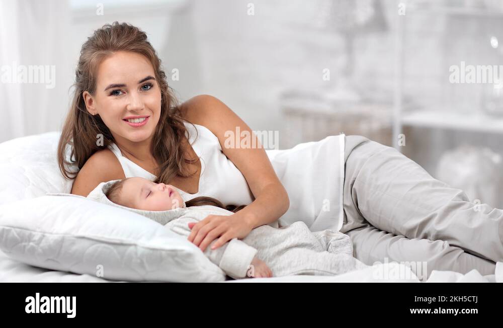 Smiling caring mother posing lulling sleepy cute baby hugging and ...
