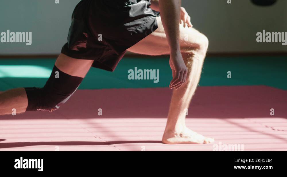 A professional young kickboxer with fit body is making a routine ...