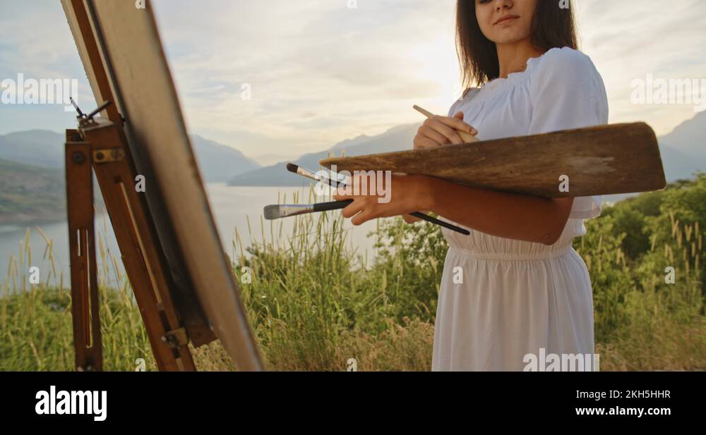 Concentrated professional female artist making an art piece on easel ...