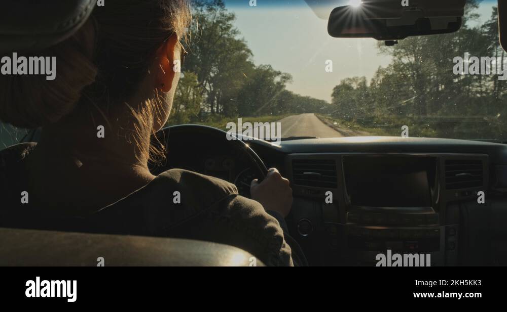 Woman drives the car while sunset. Young woman driving the car. Young ...