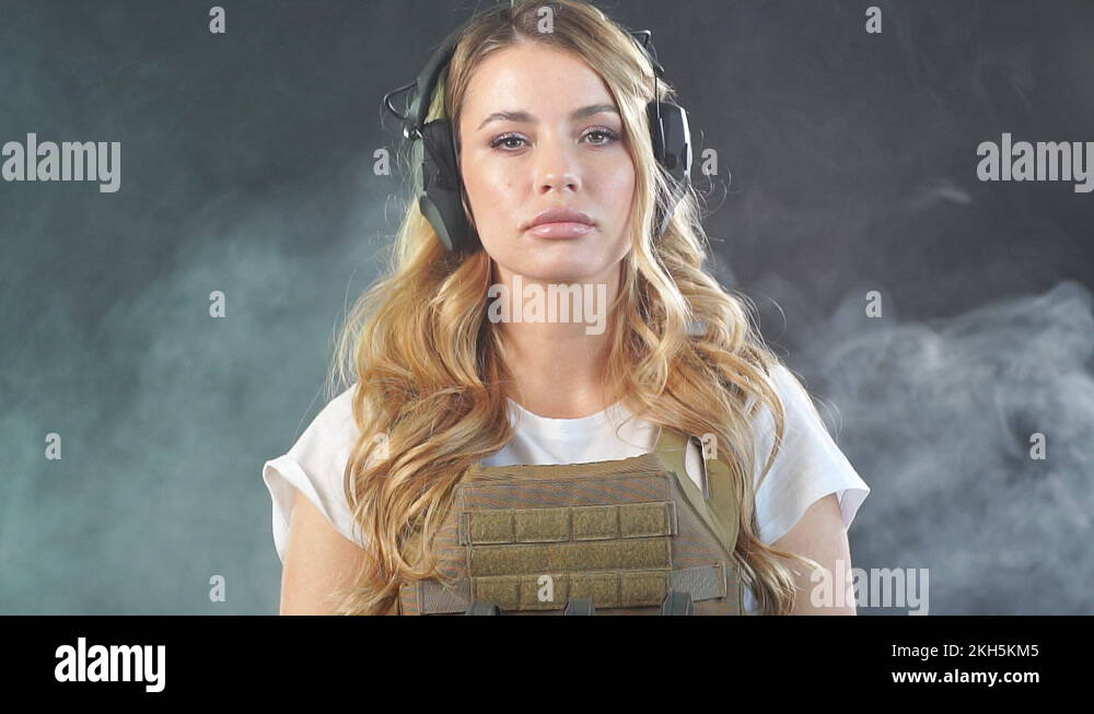 Armed blonde woman shoots with gun at a target in the darkness with ...