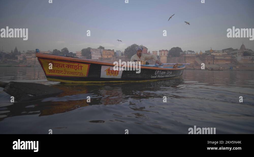 Indian men rowing boat at sunrise in the Holy river Ganges, Varanasi ...