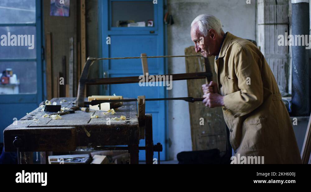 An elder carpenter is working wood with planer and saw in old carpentry ...