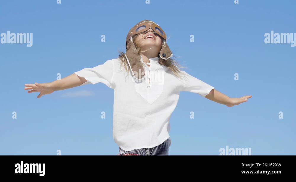 A happy little girl dressed as aviator having fun to fly with her arms ...