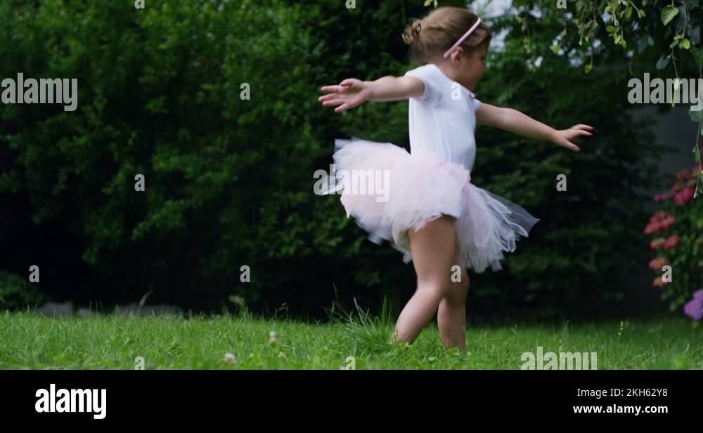 A happy little girl dressed as ballet dancer is spinning around in the ...