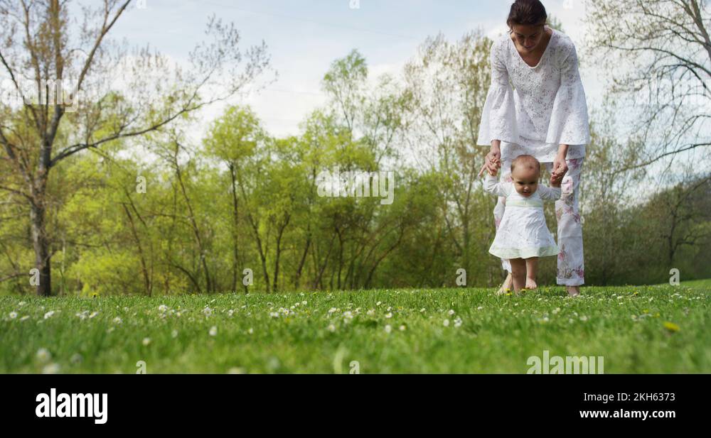 A mother is helping to her cute baby girl to make the first steps Stock ...