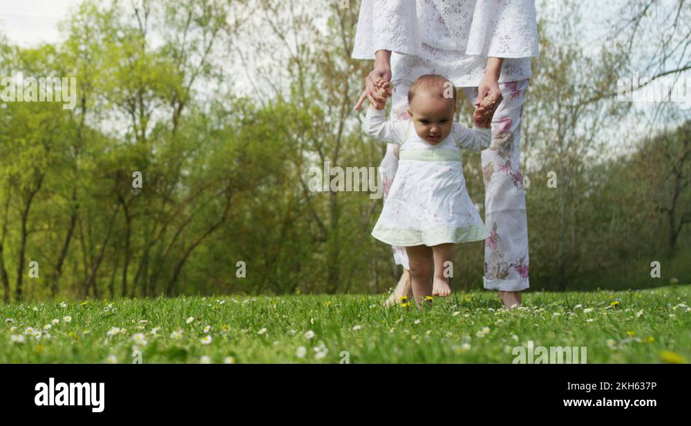 A mother is helping to her cute baby girl to make the first steps Stock ...