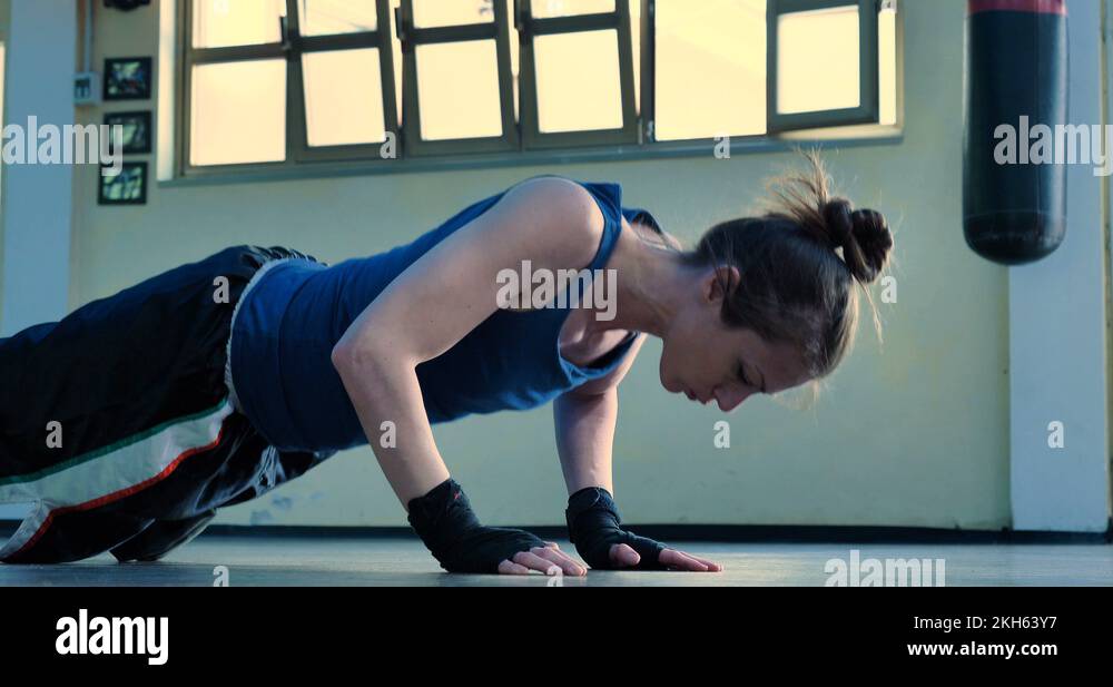 An young female boxer with fit body is making a routine workout in gym ...