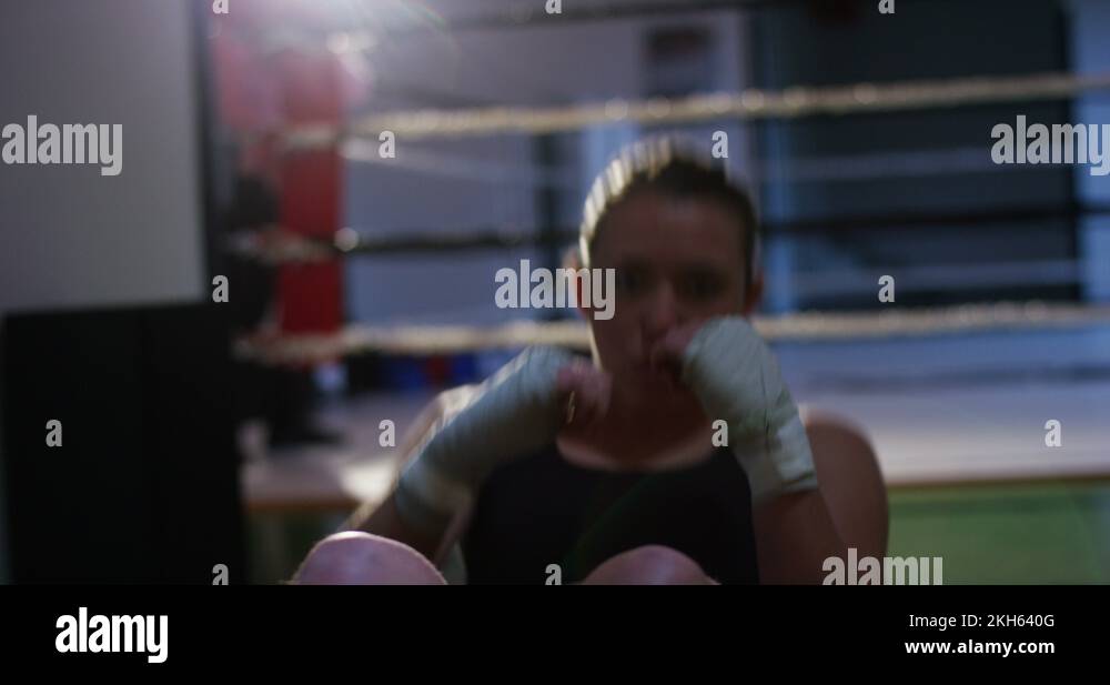 An young female boxer with fit body is making a routine workout in gym ...