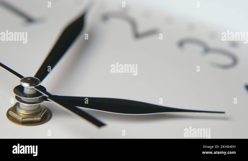 Old-looking white clock face put aslant showing twenty-five minutes ...