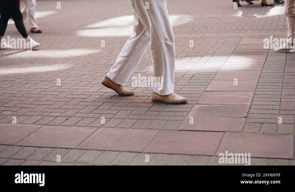 A man in white pants and brown shoes passes from left to right Stock ...