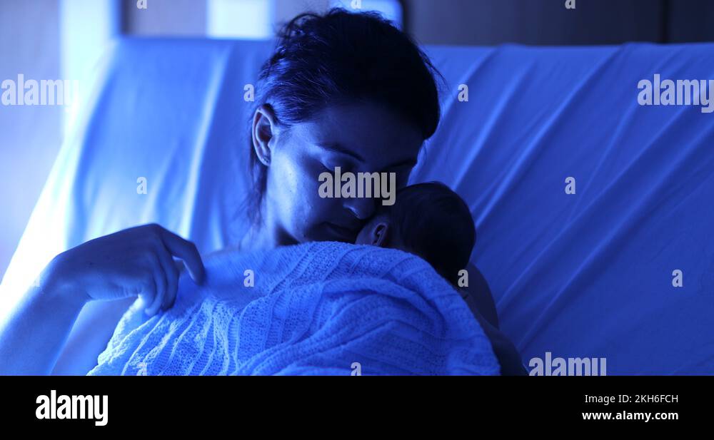 Mother holding newborn baby at hospital next to violet phototherapy ...