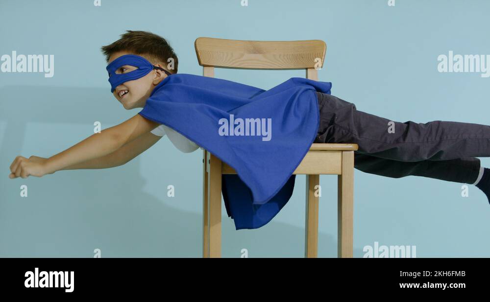 Caucasian kid boy wearing blue cape and mask, pretending to fly like a ...