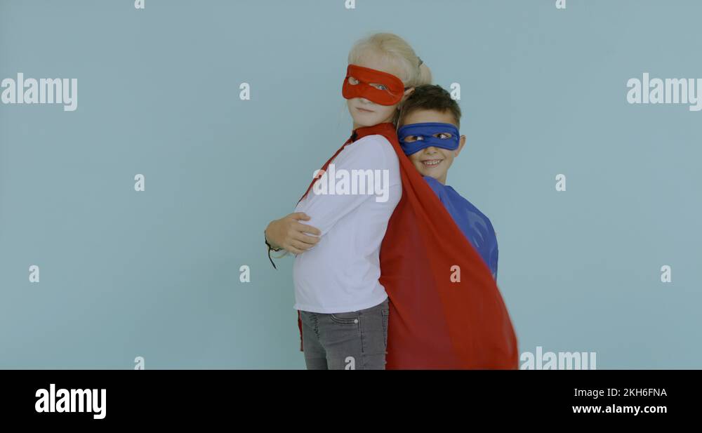 Caucasian boy and girl wearing capes and masks pretending to be ...