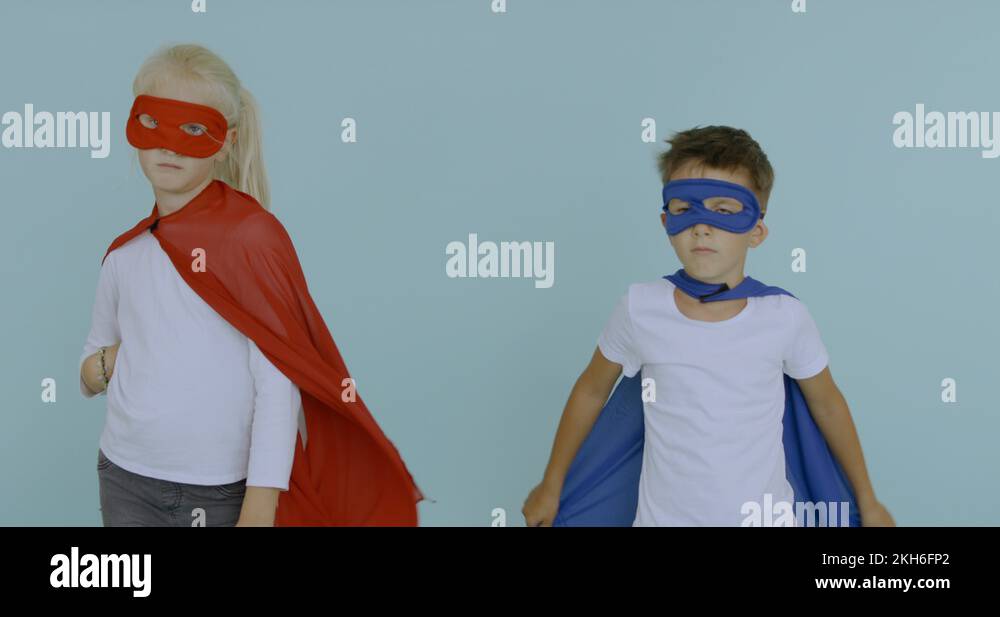 Caucasian boy and girl wearing capes and masks pretending to be ...