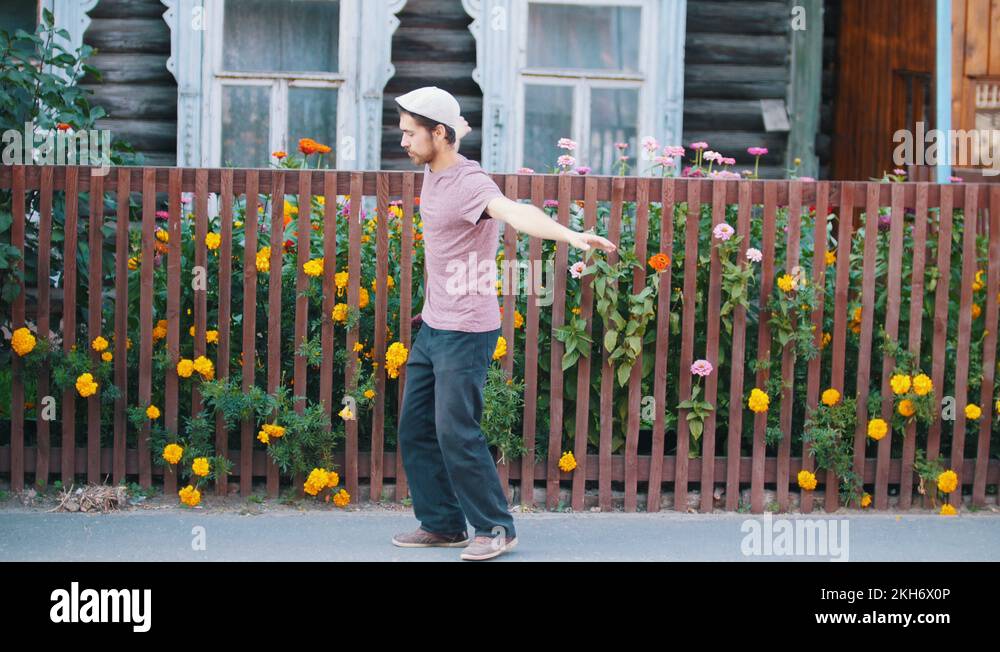 A russian man dancing russian folk dance by the fence with flowers ...