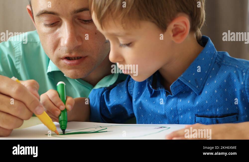 A father spends time drawing with colored pencils with his son ...