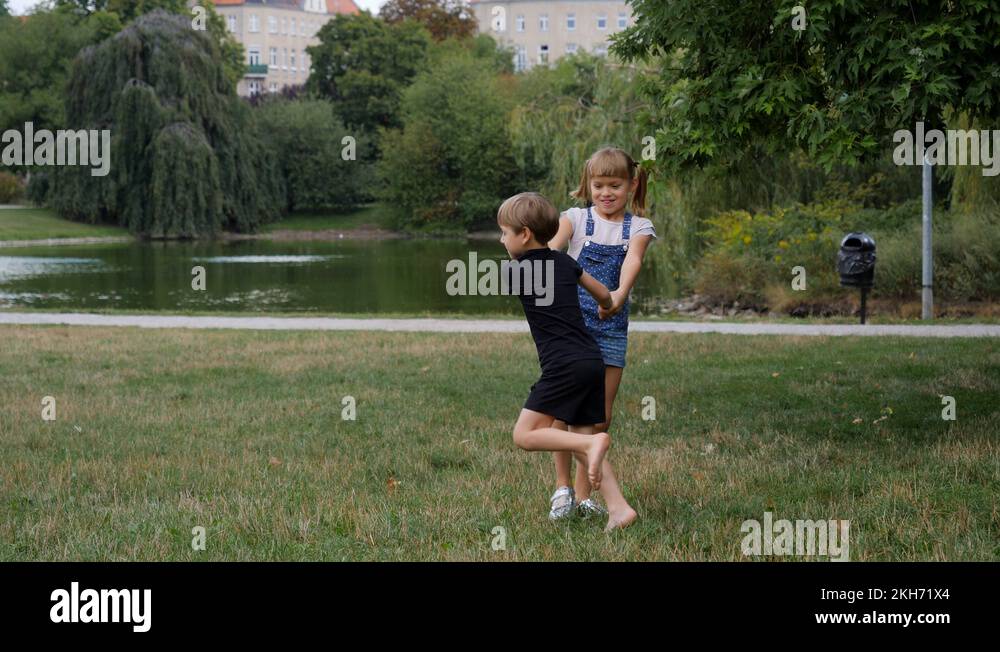 Funny children play together on park grass dancing jumping having fun ...