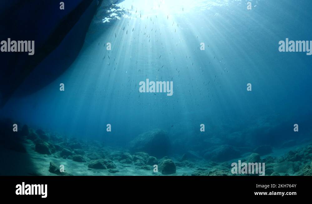 sun beam sun rays sun shine underwater under the boat fish around Stock ...