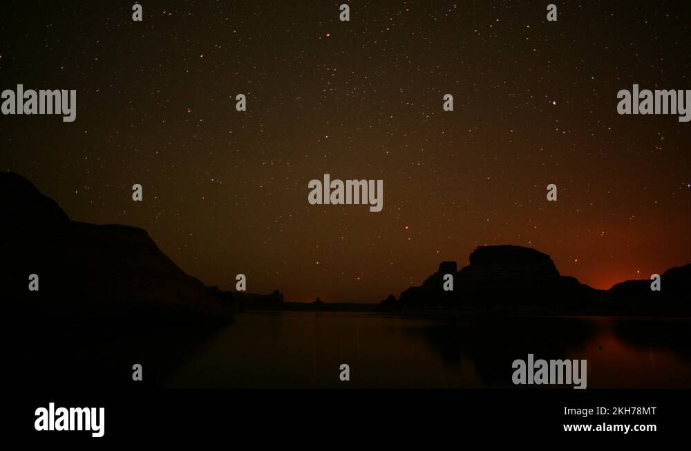time lapse movie of a red rock region as the stars and race over a lake ...