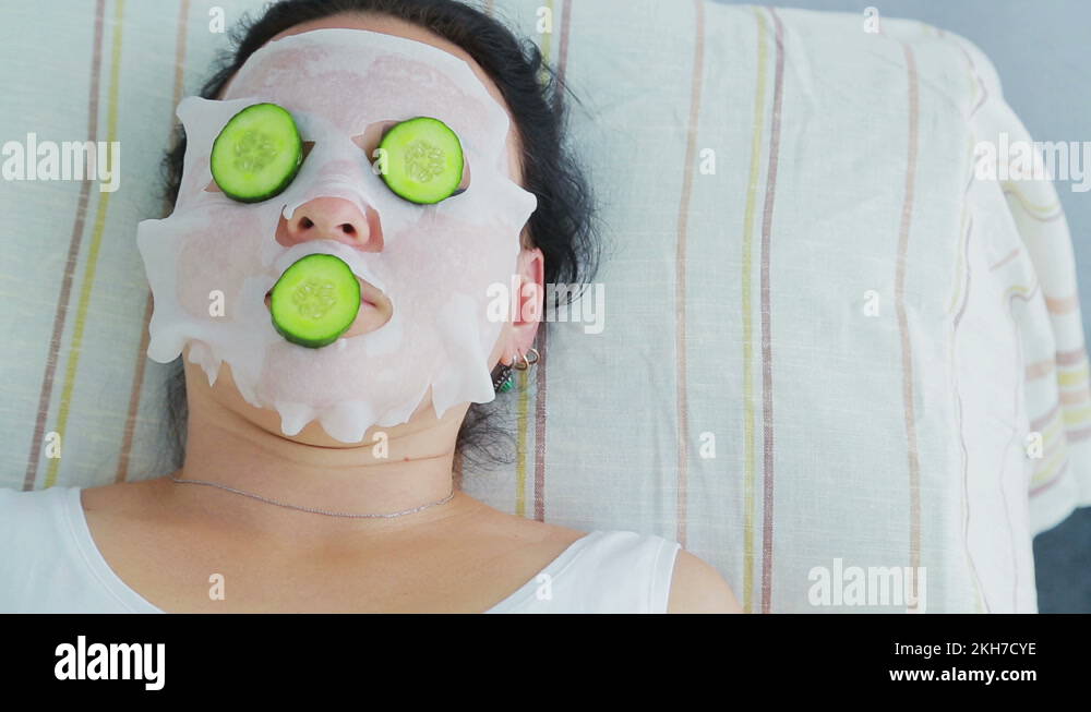 A male beautician makes a female client a vegetable therapy on her face ...