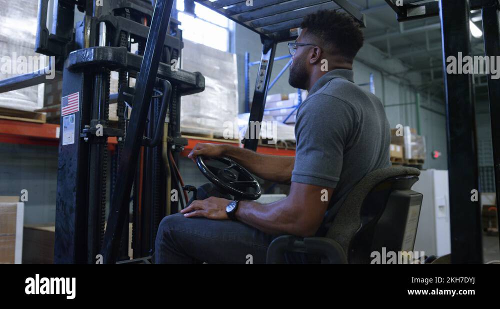 Warehouse worker using a forklift to lift shipment pellet in warehouse ...