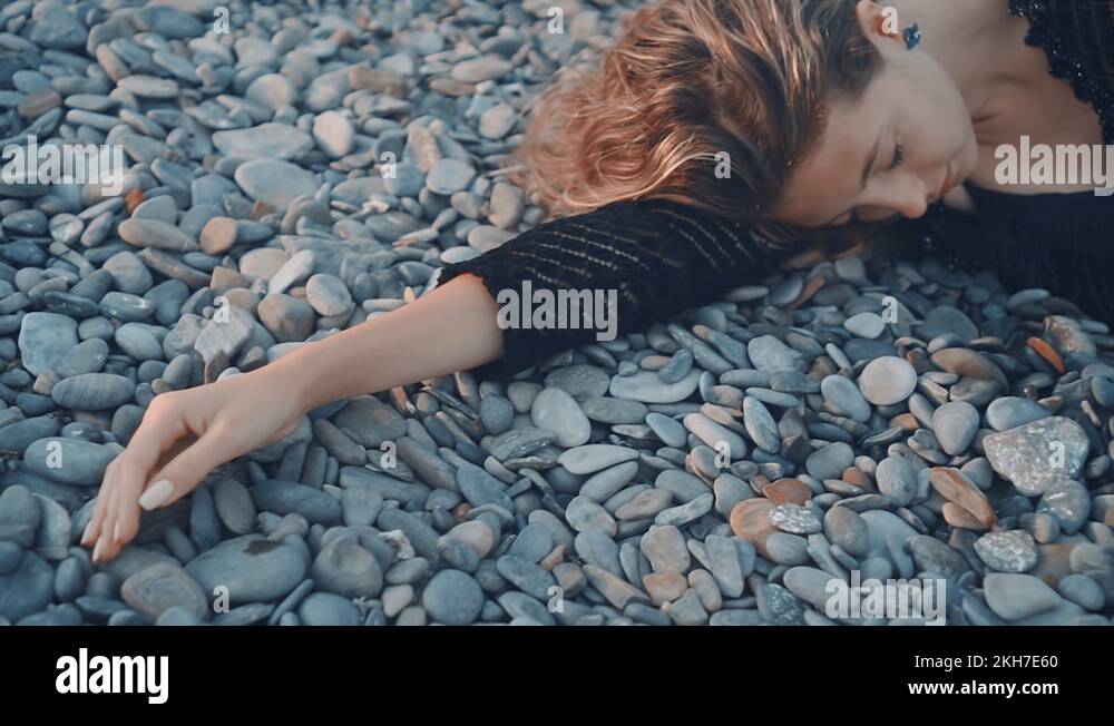 A young girl lying on the seashore unconscious, without movement ...