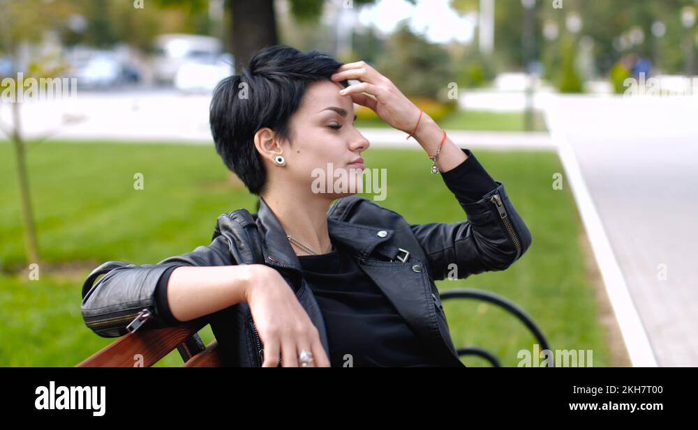 short-haired brunette girl sitting on a bench straightening her hair ...