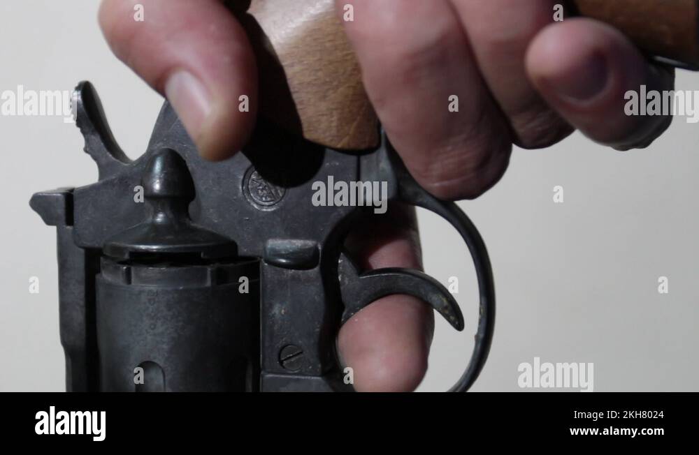 man's hand holds the gun in his hand, loads and pulls the trigger Stock ...