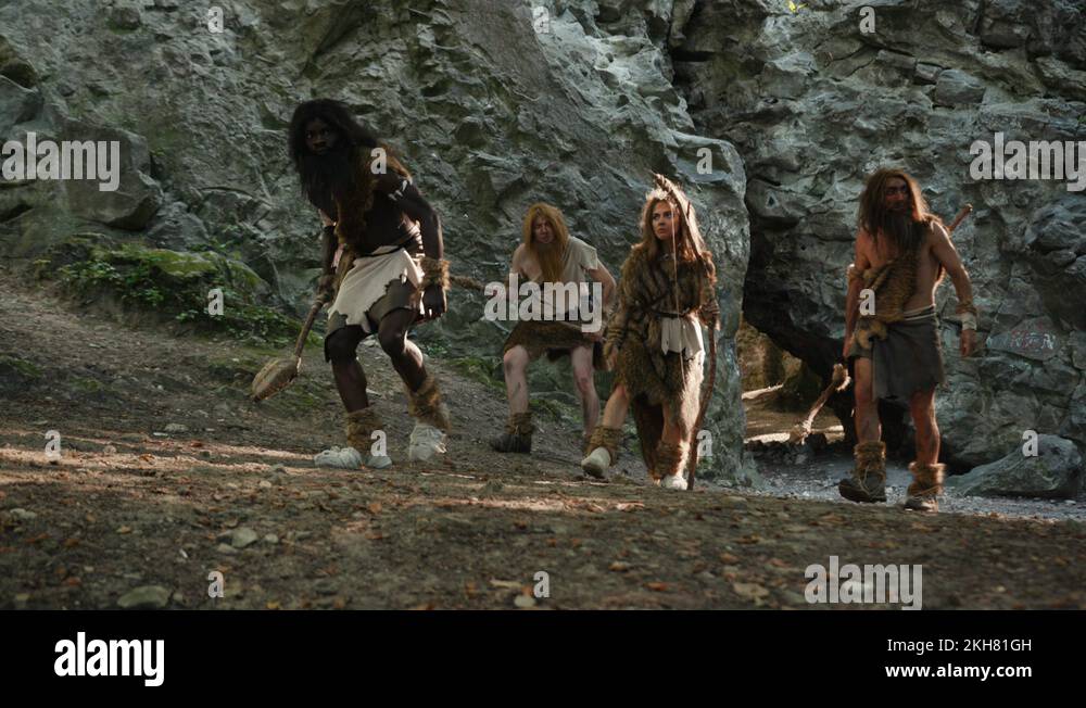 Primitive tribe of wary neanderthals walking slowly in prehistoric ...