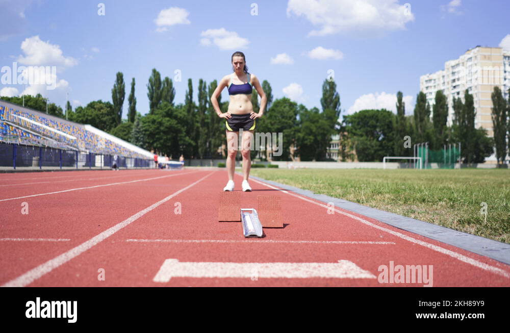 Young brunette girl athlete in position to start running on stadium ...