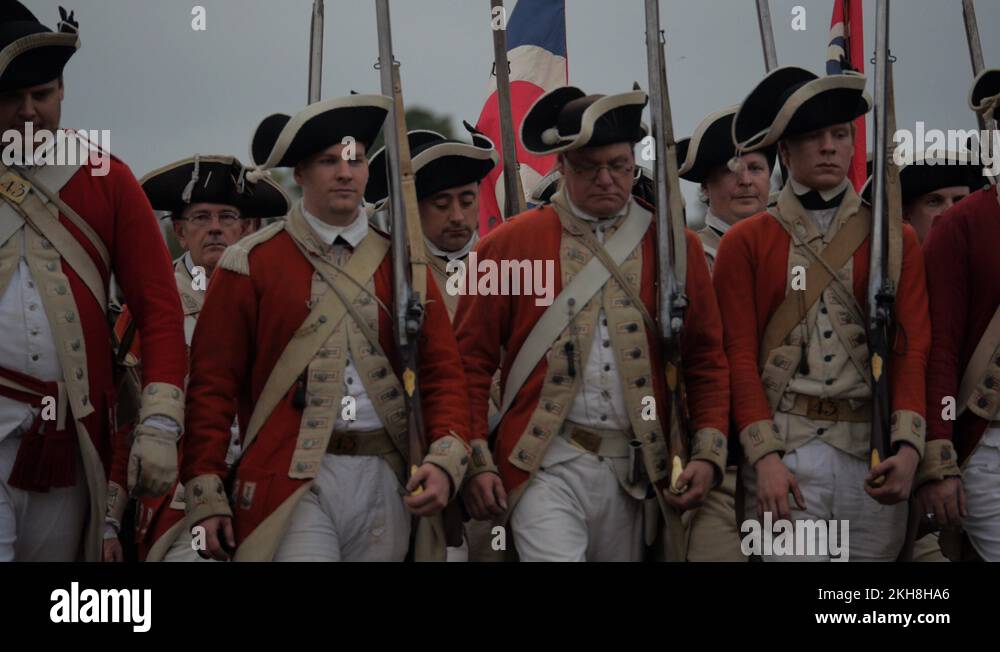 British Redcoat re-enactors marching into battle with flags & muskets ...