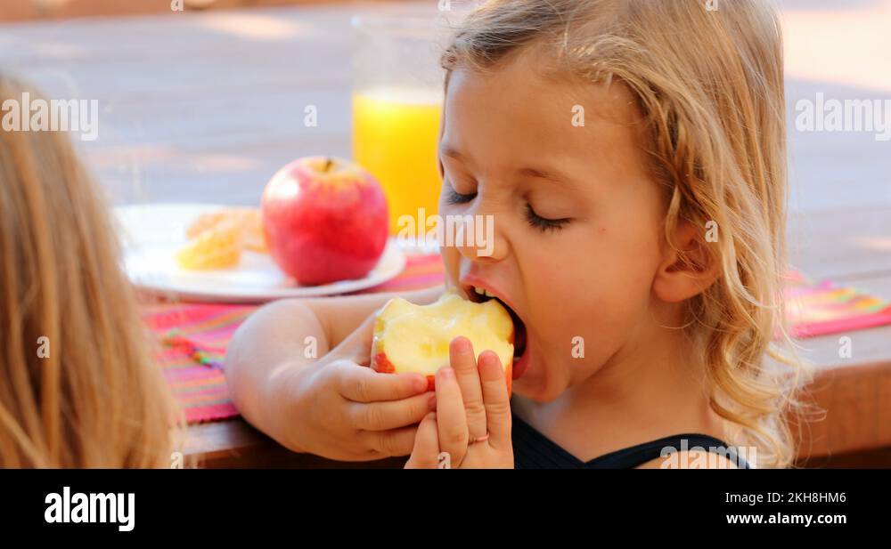 Little girl biting apple eating fruit outside Stock Video Footage - Alamy