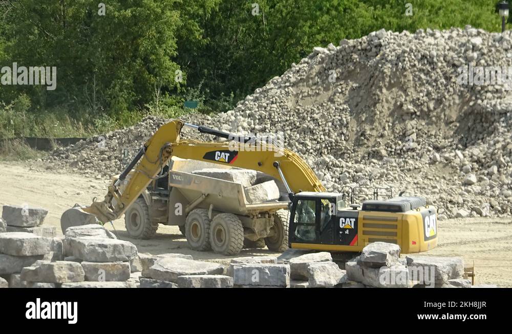 Excavator loading boulders to a dump truck in a construction project ...