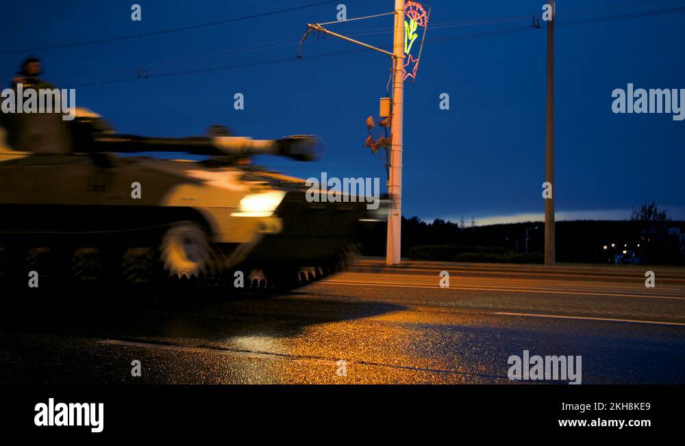 A convoy of military equipment rides through the city at night with ...