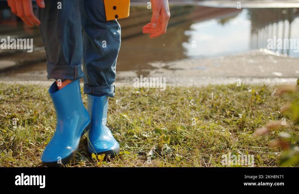 Close-up of hand taking off rubber boot from bare foot and pouring out ...
