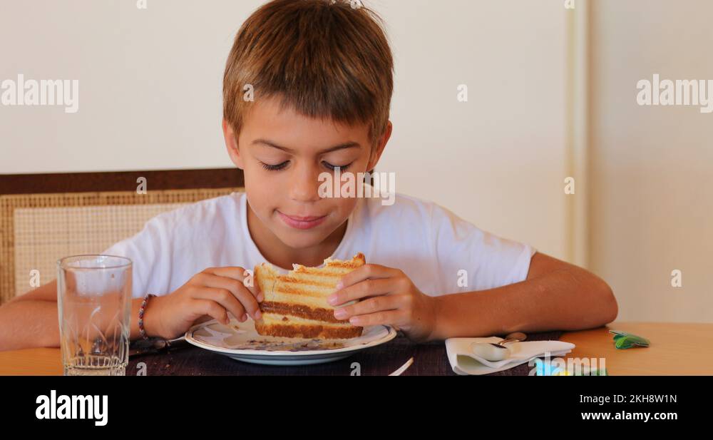 Child eating sandwich handsome young boy taking a bite of his ham and ...