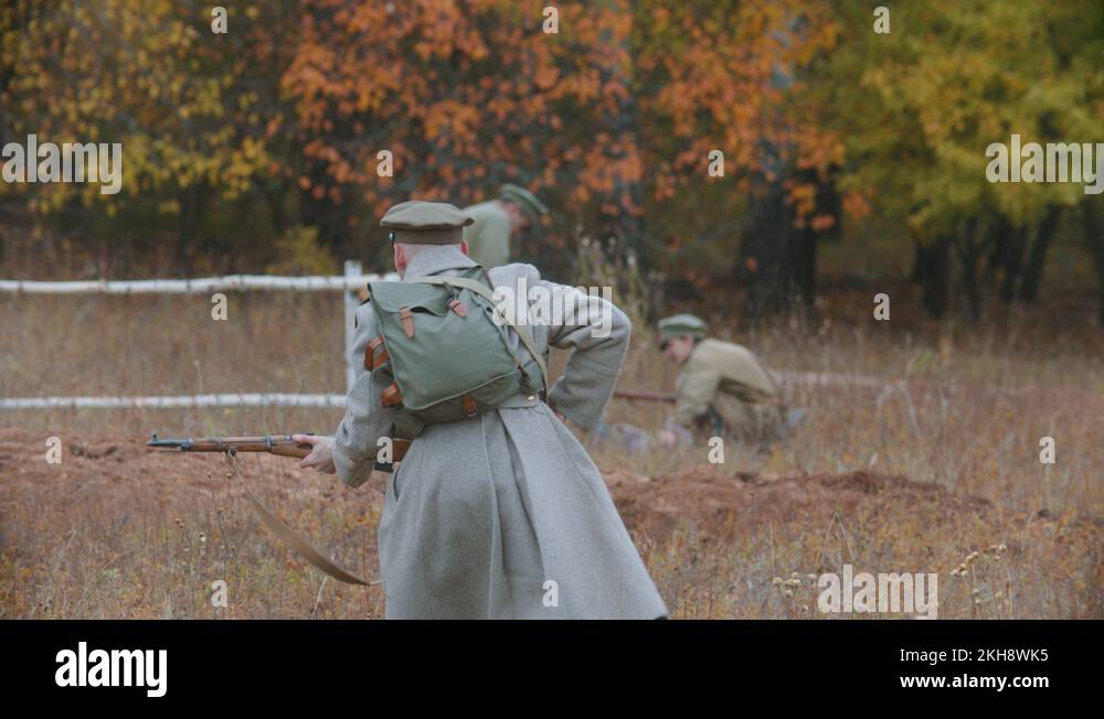 A soldier running on the battlefield - two men helping to stand up to ...