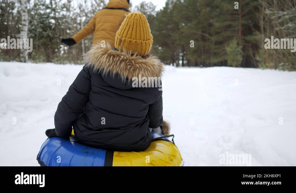 Man is pulling tubing and sliding his wife and child in the snow ...